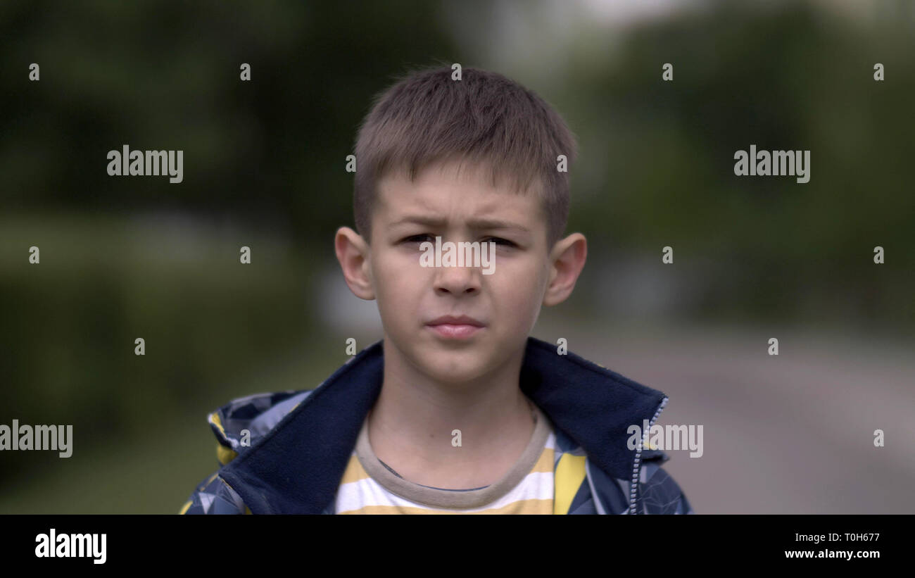 portrait of a serious boy with a tence glance looking at the camera ...