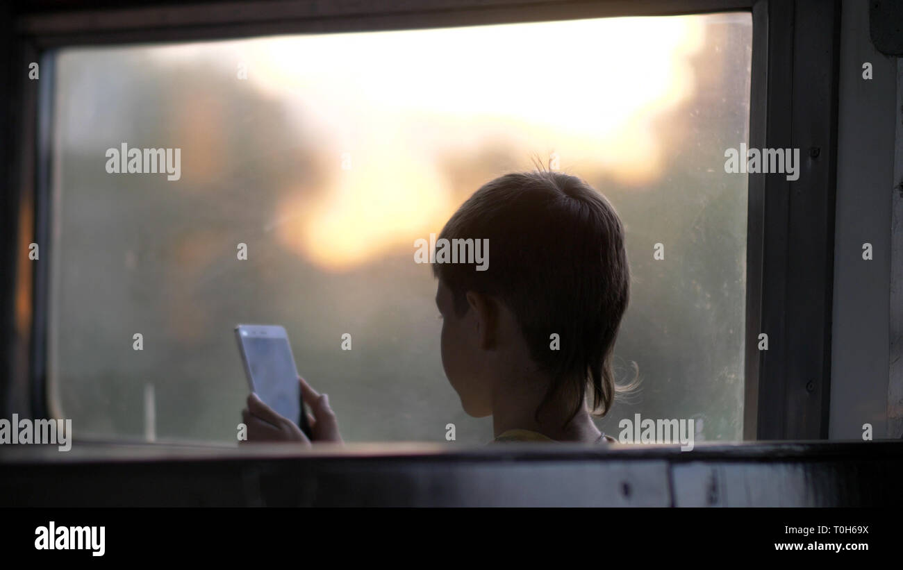 Boy Rides On A Train In The Evening And Uses A Phone, Back View Stock ...