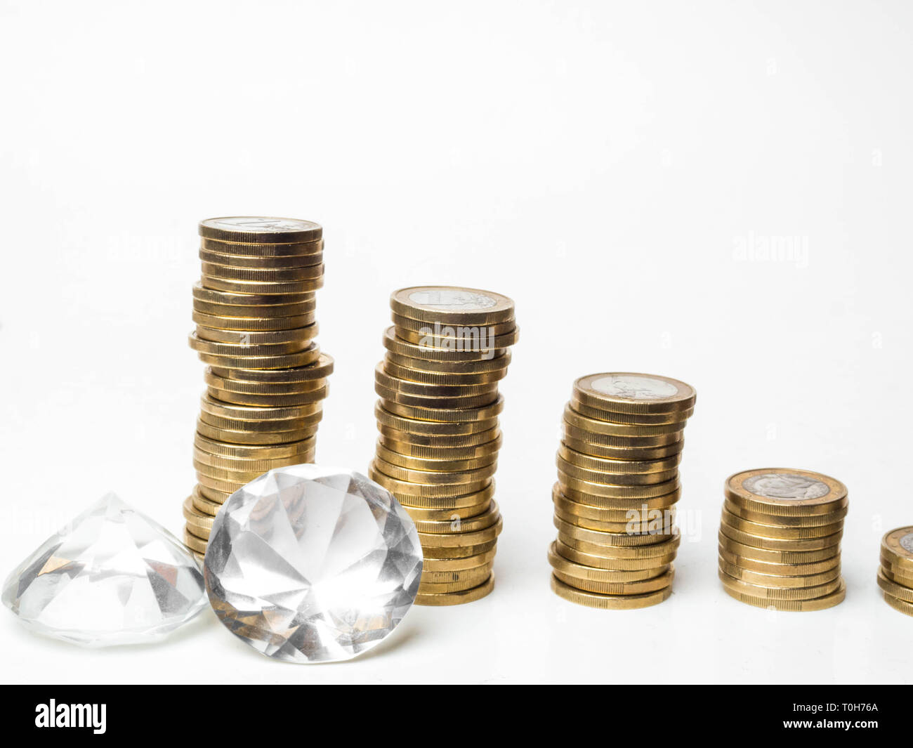 euro coins tower , big diamonds lying on white table Stock Photo - Alamy