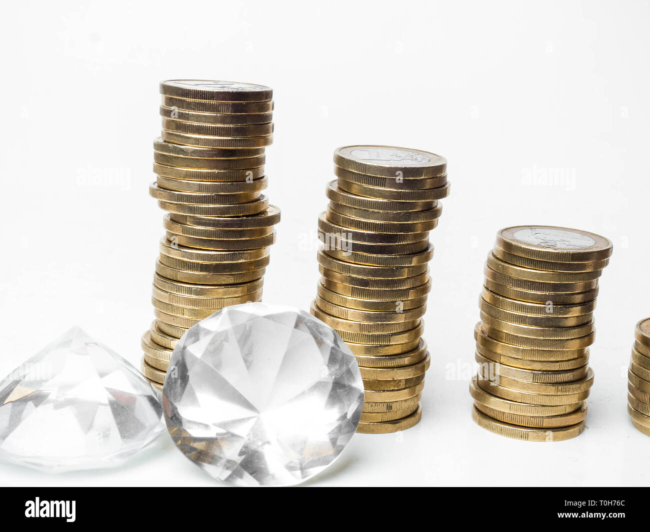 euro coins tower , big diamonds lying on white table Stock Photo - Alamy