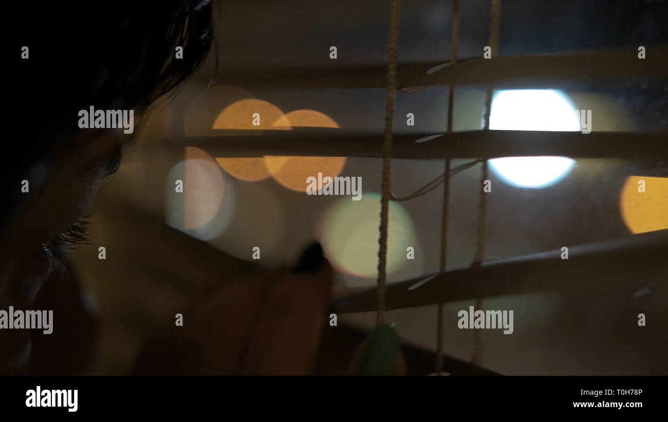 young brunette with brown eyes peeks through the window with her finger ...