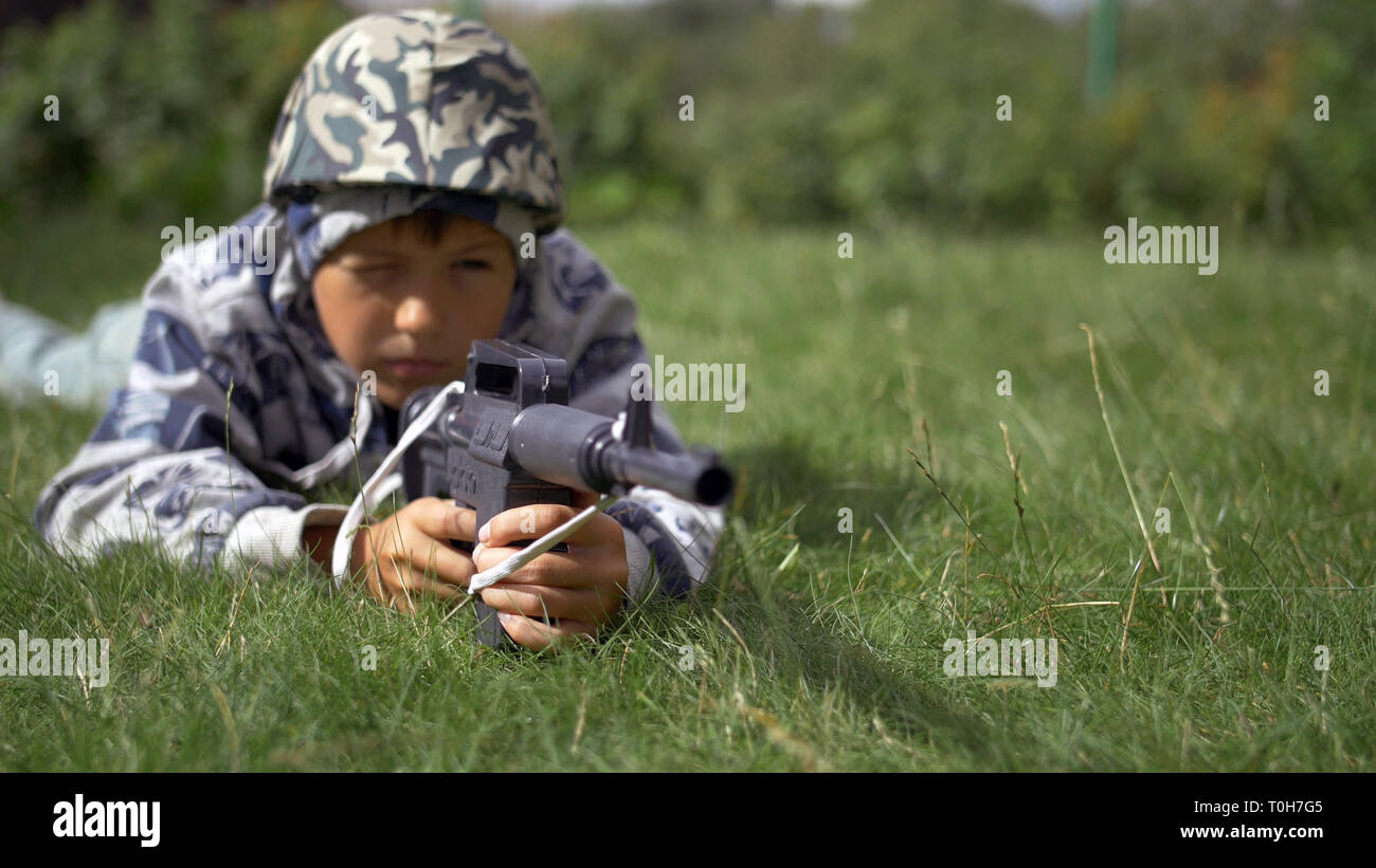boy in camoflauge playing war shoots a toy gun Stock Photo - Alamy