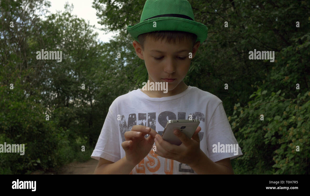 Boy with mobile phone walking outdoors, uses touchscreen smartphone ...