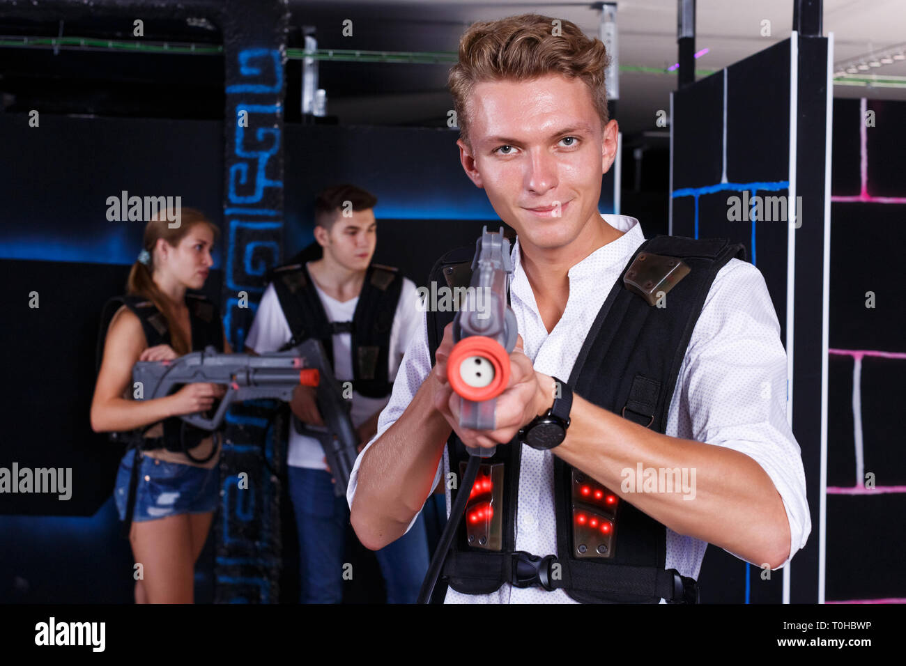 Portrait of smiling young guy holding laser pistol playing laser tag ...