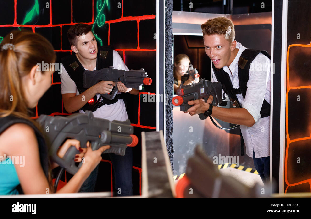 Two cheerful smiling laser tag teams playing enthusiastically and ...