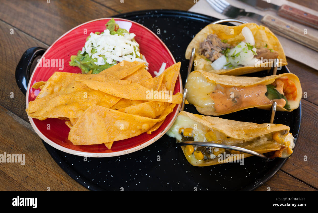 Traditional Mexican tacos with various fillings served with guacamole ...