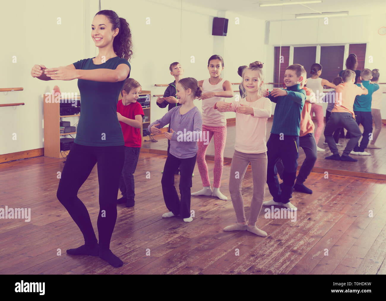 Group of children with female teacher studying ballet in dance class ...