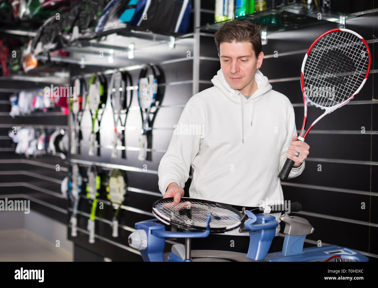 Adult man is looking on the tennis racket in the time repairs it ...