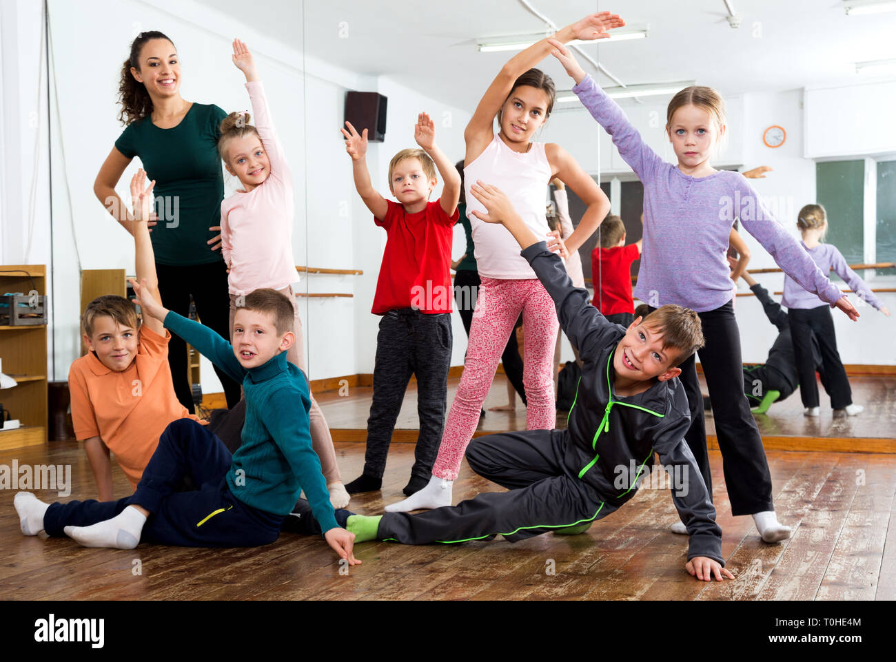 Smiling children studying modern style dance in class and their teacher ...