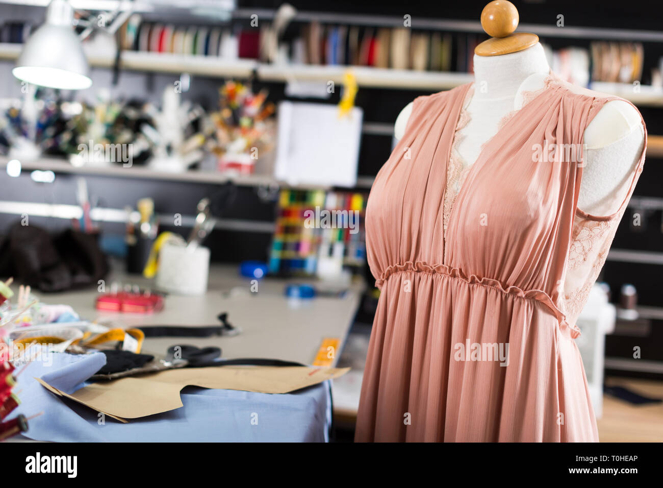 Workplace with mannequin with dress in sewing shop of variety clothes ...