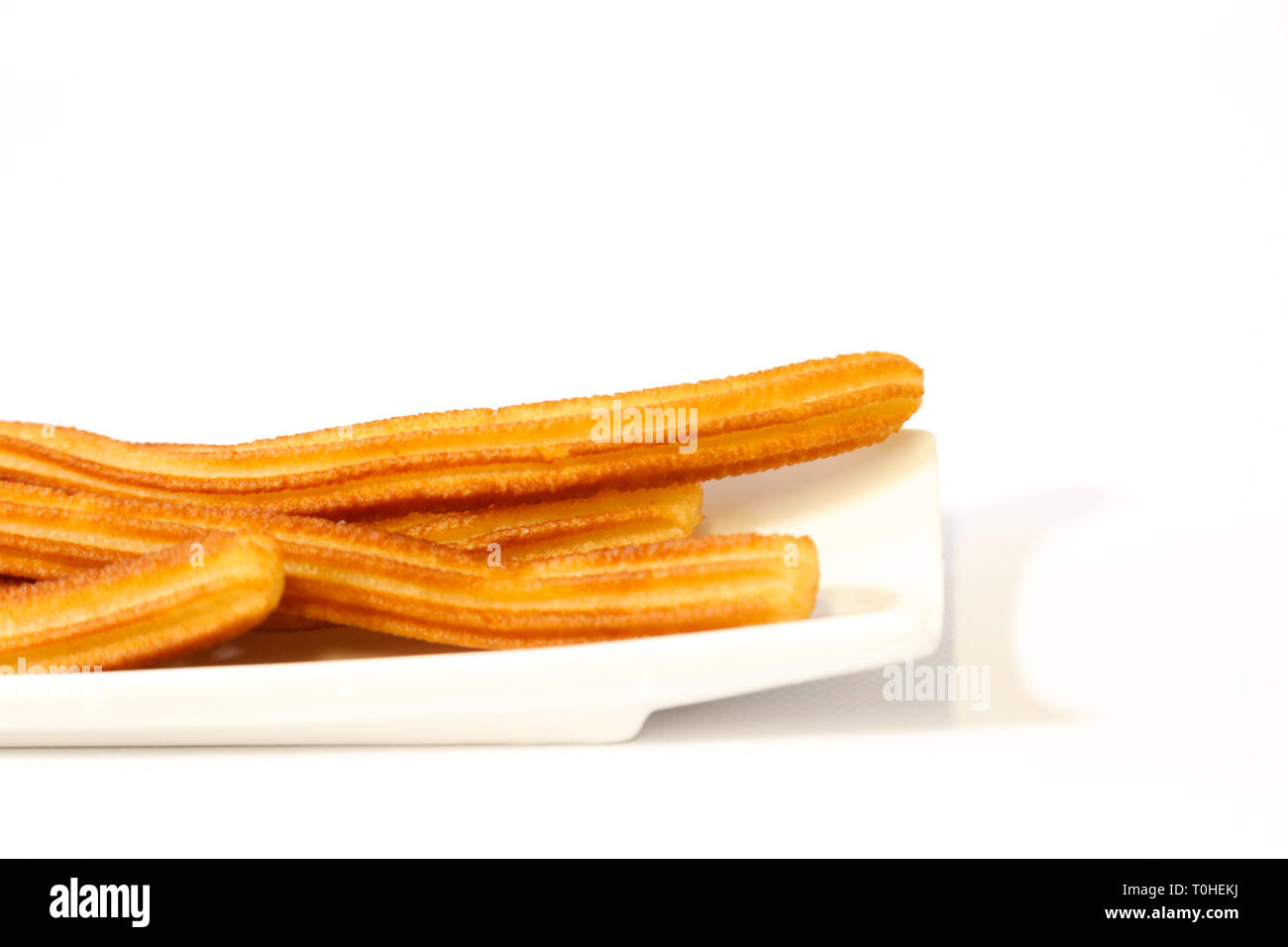 spanish fritters on a white dish with white background Stock Photo - Alamy