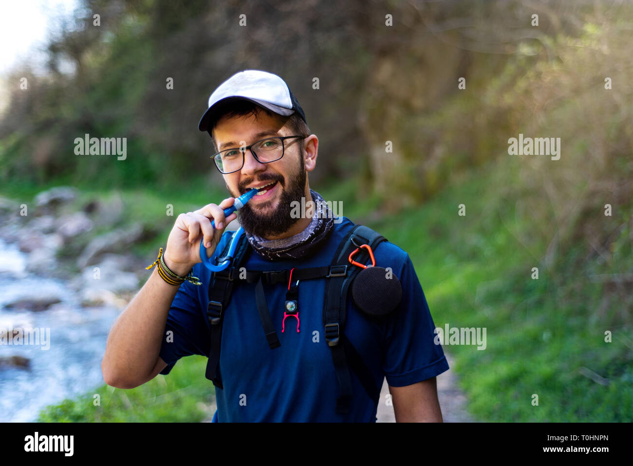 Man hiking by the river and hydrating with water pipe Stock Photo - Alamy