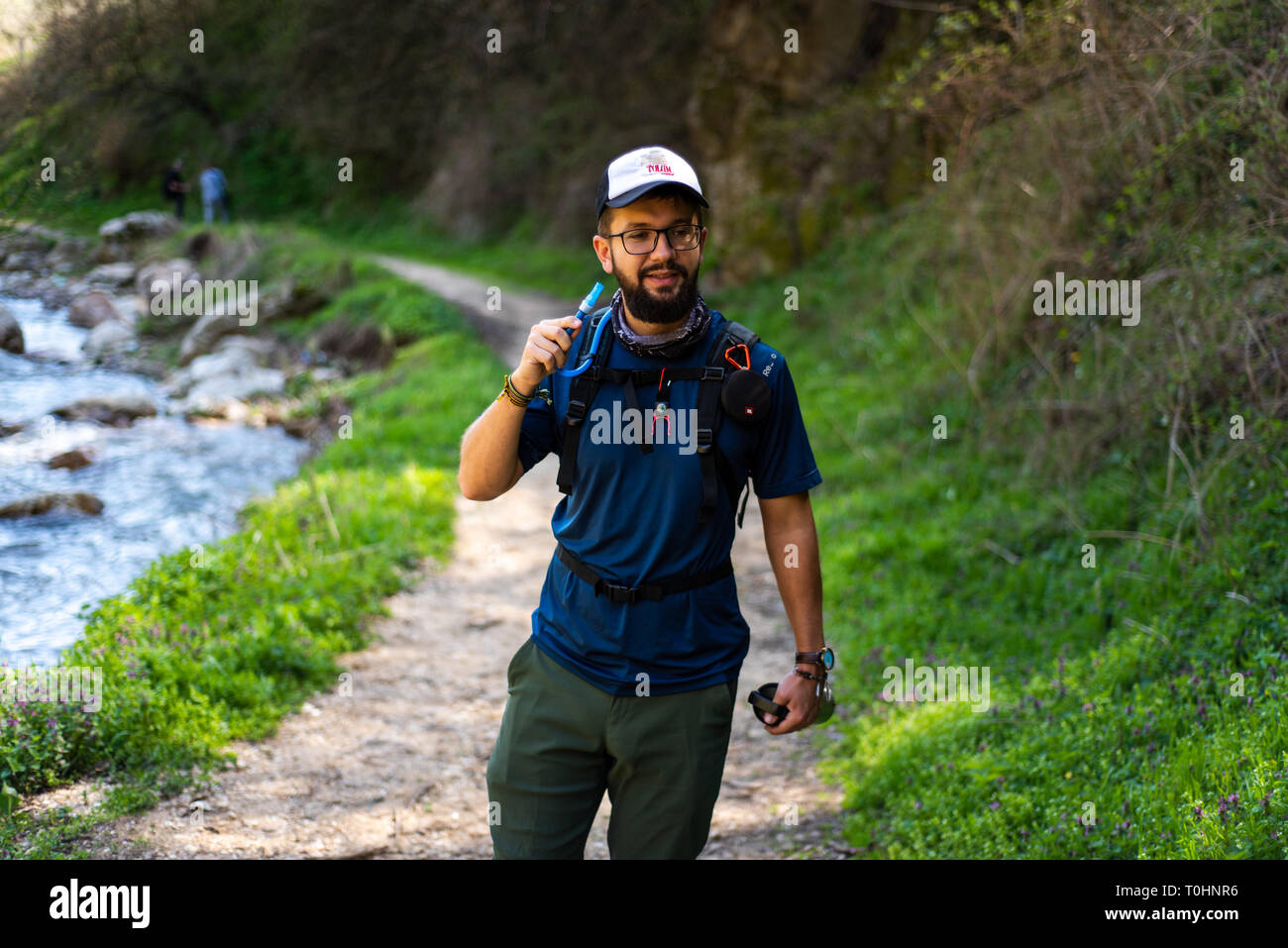 Man hiking by the river and hydrating with water pipe Stock Photo - Alamy