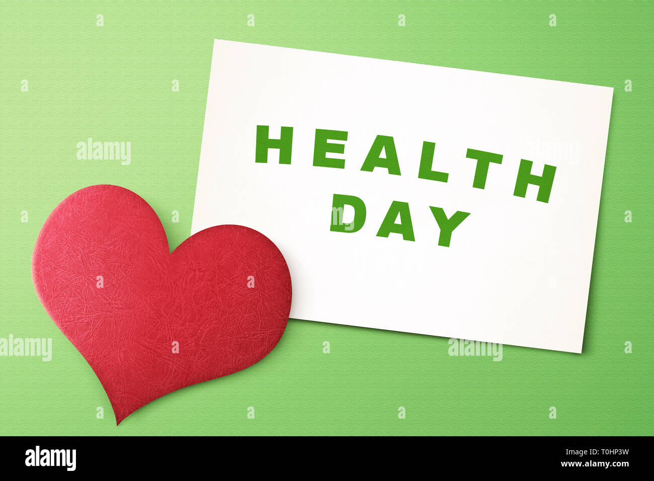 Red heart and white paper with Health day message over green background ...