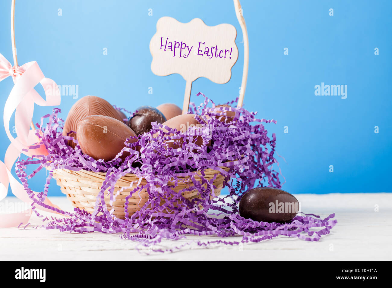 Image of chicken, chocolate eggs, purple decorative paper in basket ...