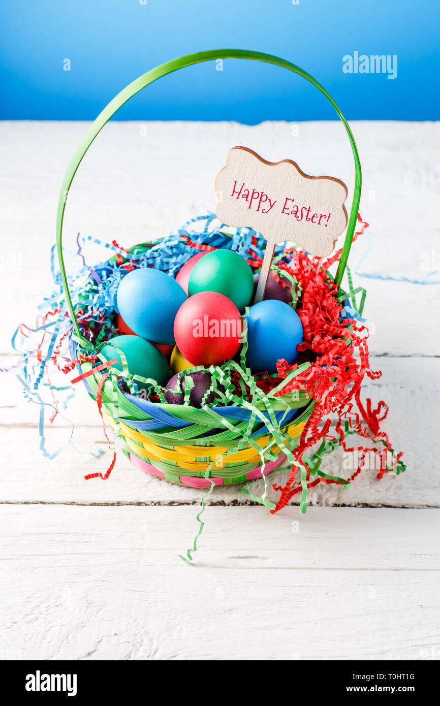 Image of basket with colorful eggs on empty blue background on wooden ...