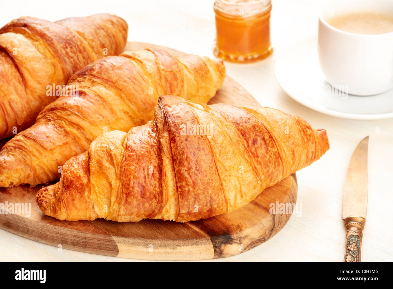 A high key closeup photo of a breakfast with croissants, coffee, and ...