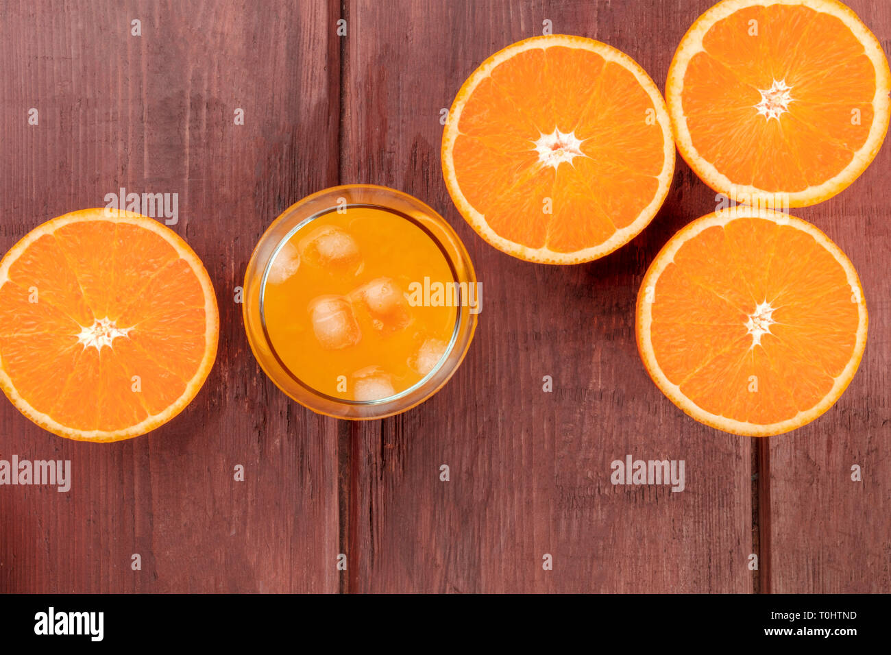 A closeup photo of a glass of fresh orange juice with orange halves ...