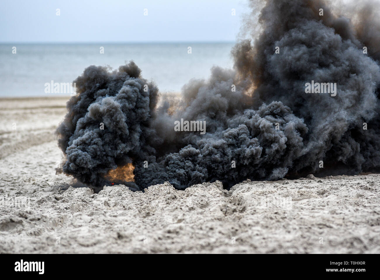 Explosion on the beach, billowing black smoke Stock Photo - Alamy
