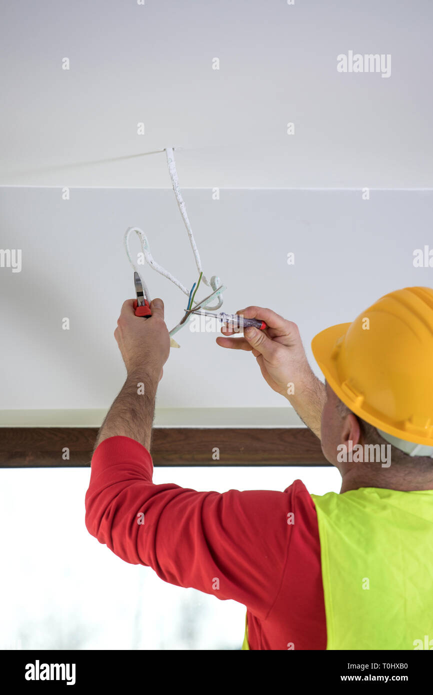 electrician service. Installer works with cable on ceiling , electrical ...