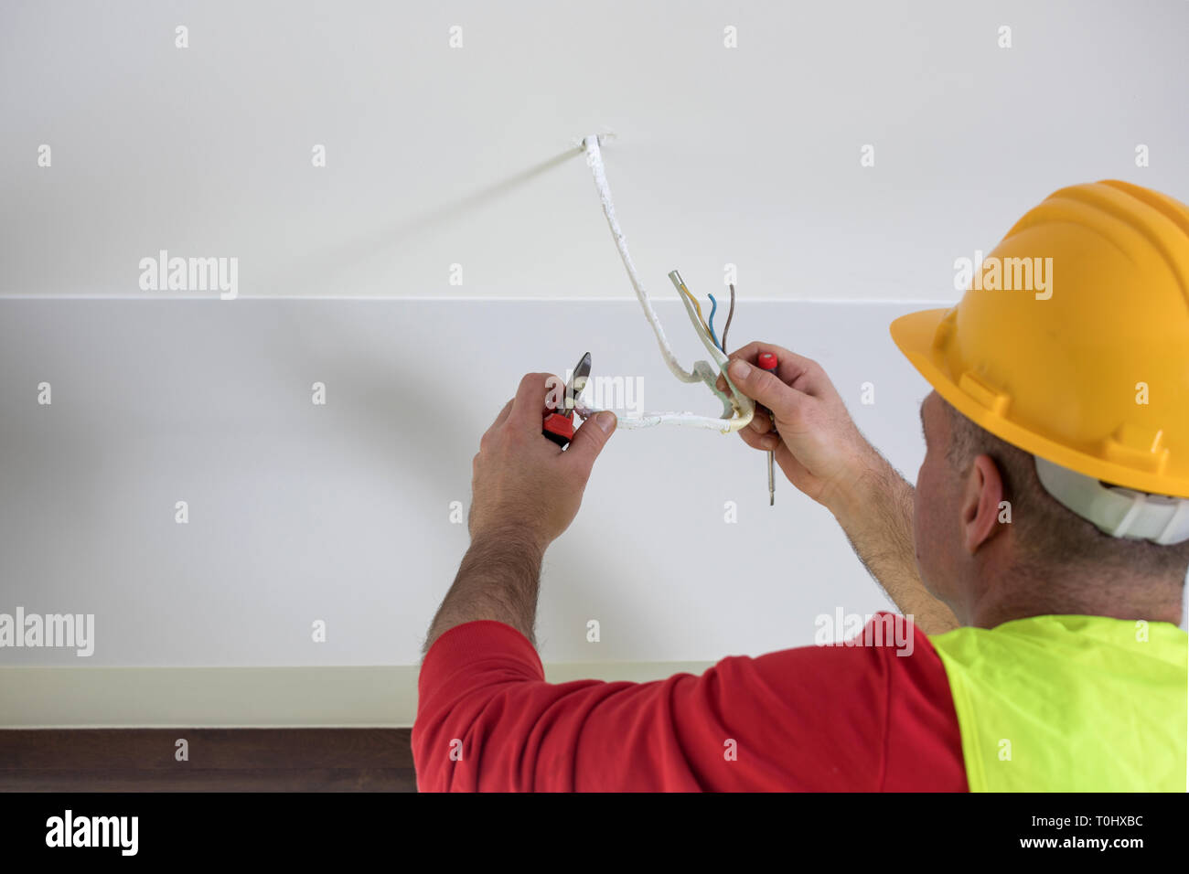 electrician service. Installer works with cable on ceiling , electrical ...