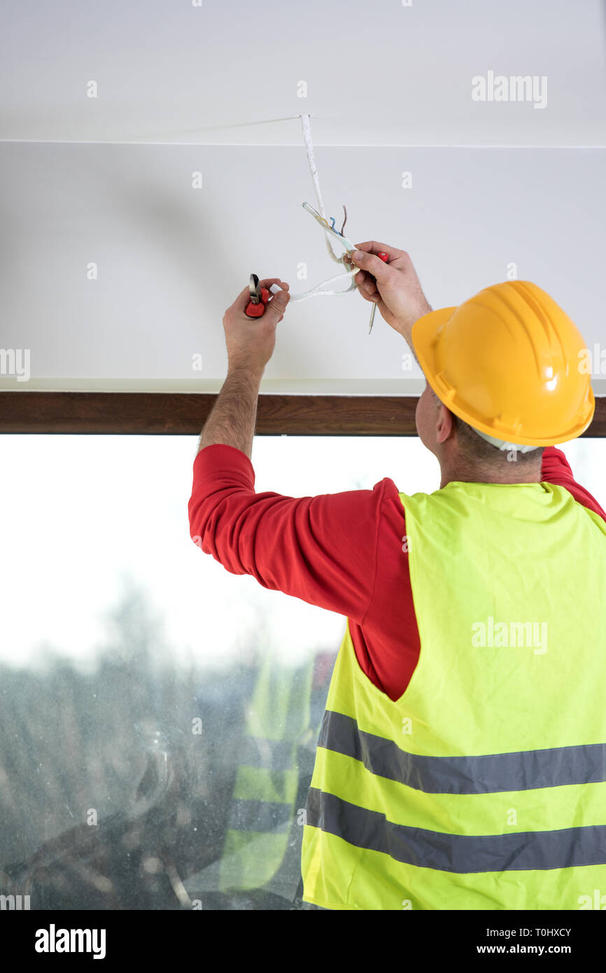 electrician service. Installer works with cable on ceiling , electrical ...