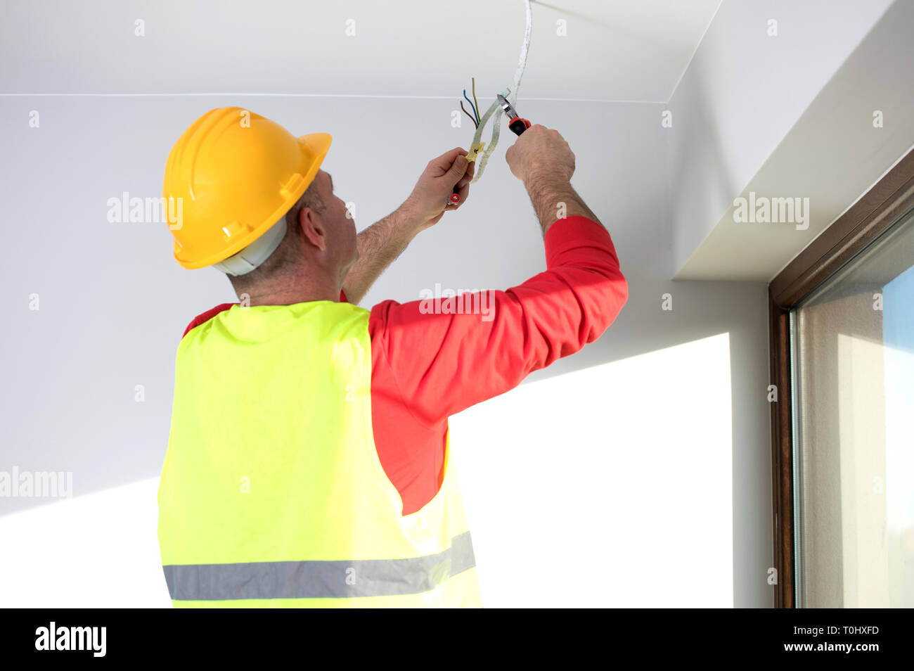 electrician service. Installer works with cable on ceiling , electrical ...