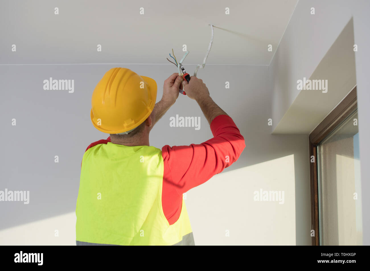 electrician service. Installer works with cable on ceiling , electrical ...