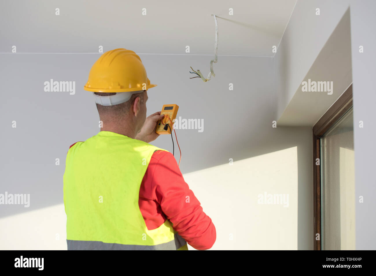 electrician service. Installer works with cable on ceiling , electrical ...