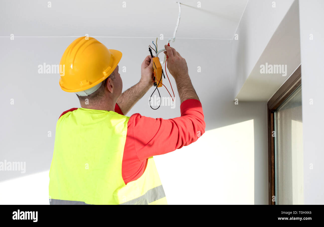 electrician service. Installer works with cable on ceiling , electrical ...