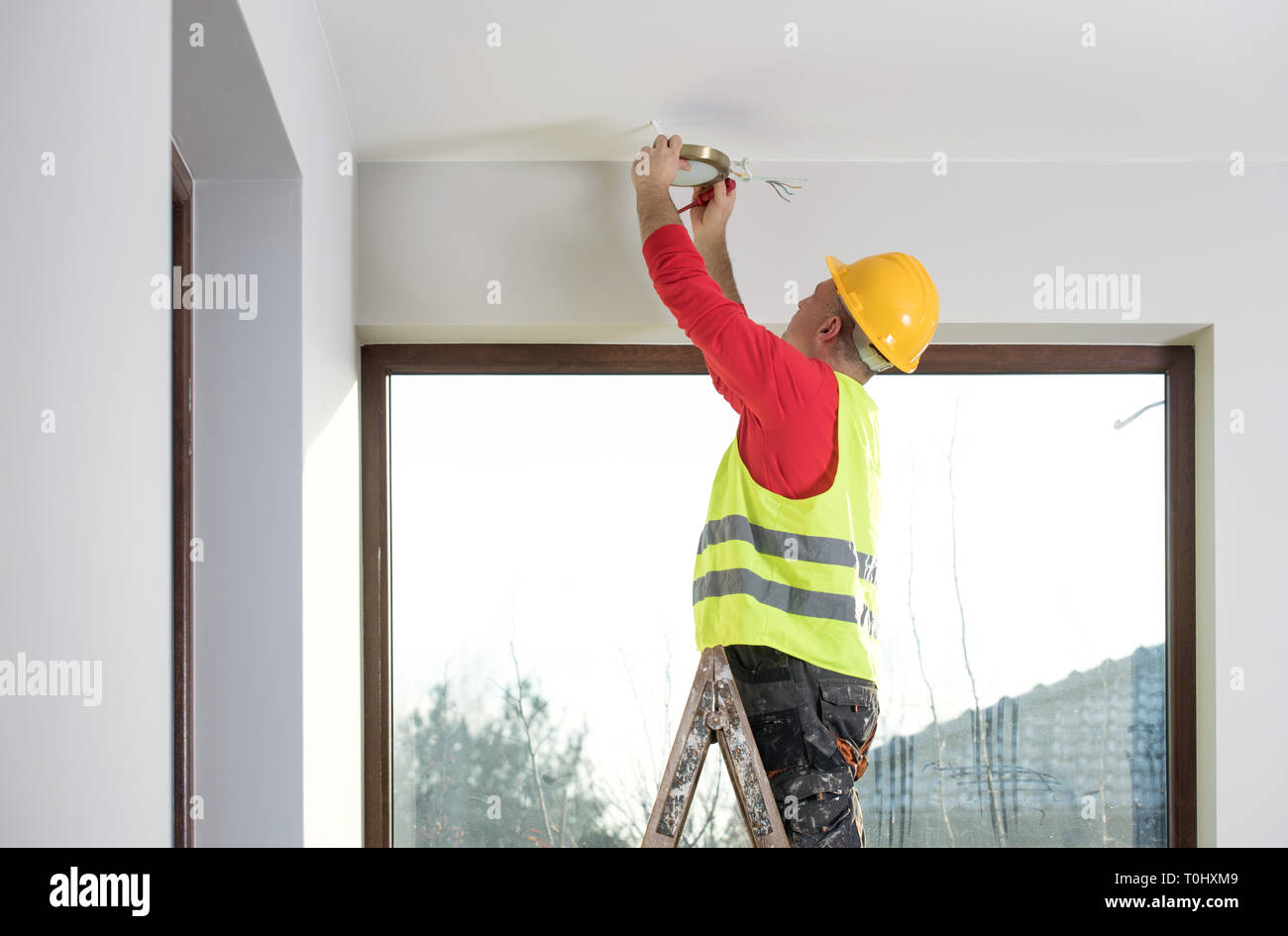 electrician service. Installer works with cable on ceiling , electrical ...