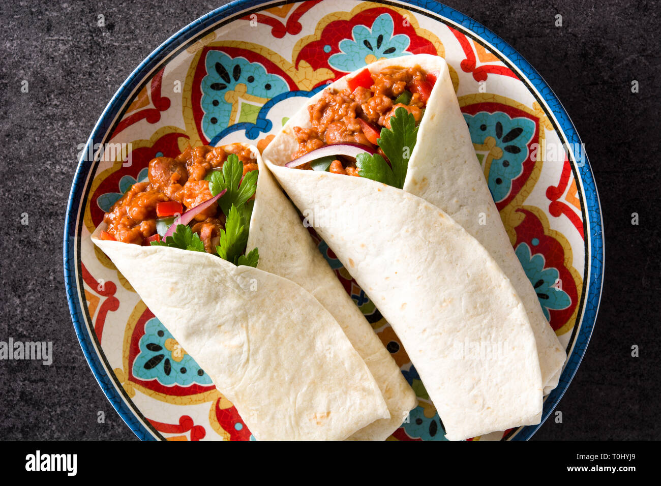 Typical Mexican burrito wrap with beef, frijoles and vegetables on ...