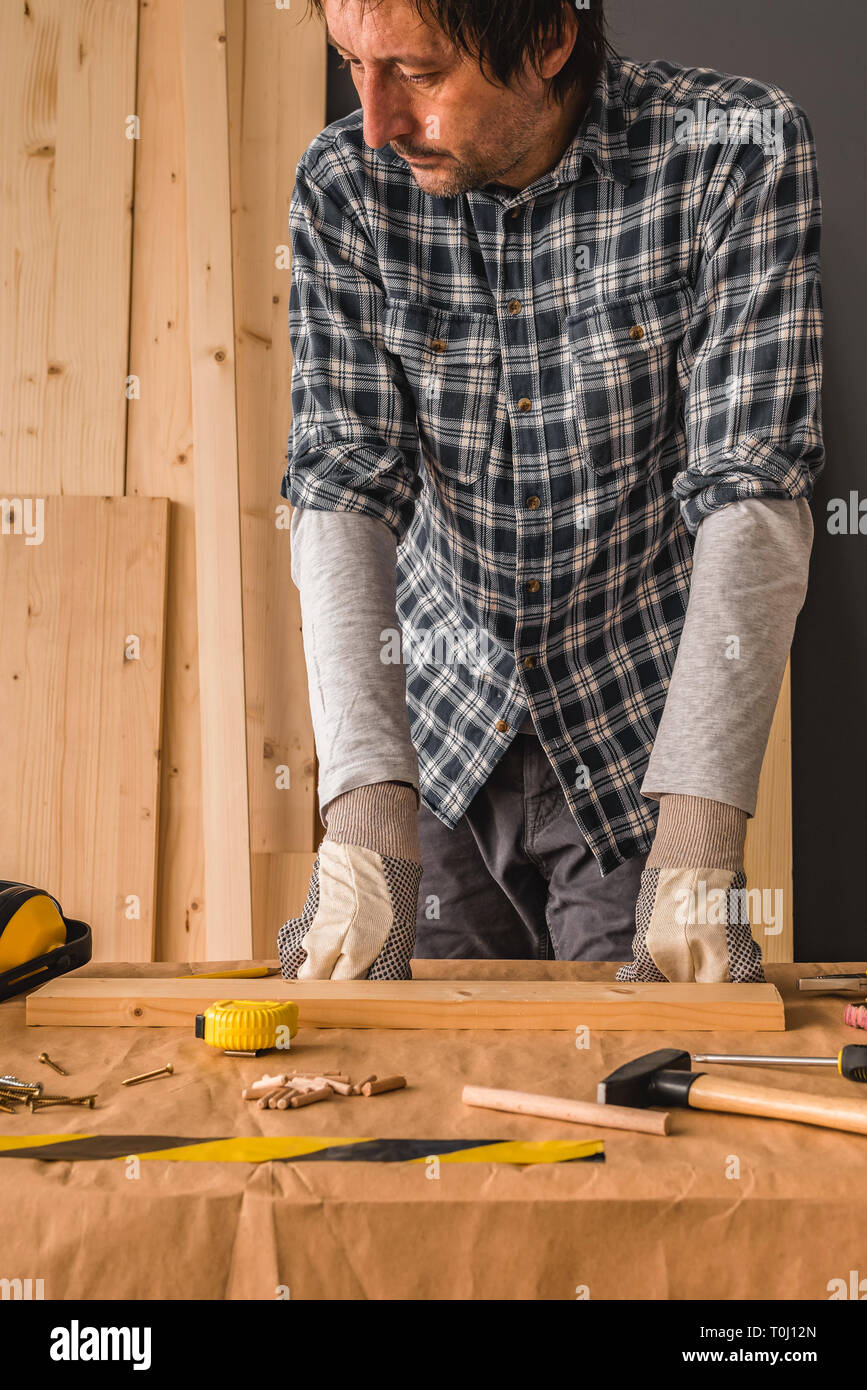 Carpenter is planning woodwork project in workshop, standing above the ...