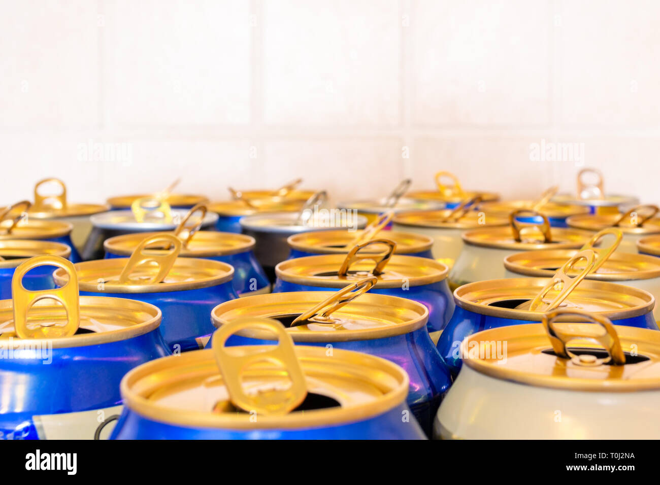 "Wide-mouth" blue and orange drink cans on a tiled background, with the ...