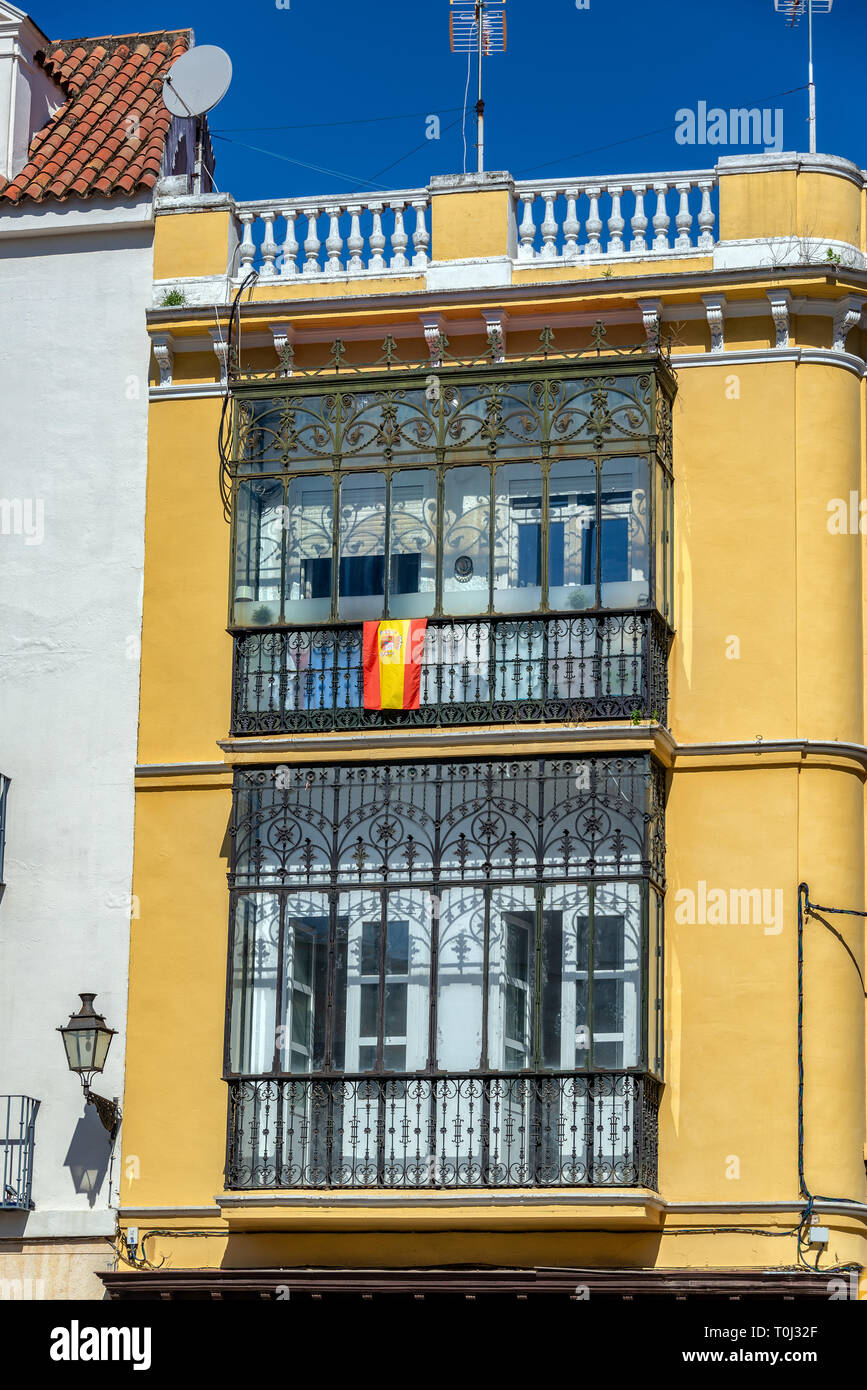 Spanish flag hanging from the balcony of an old yellow building in ...
