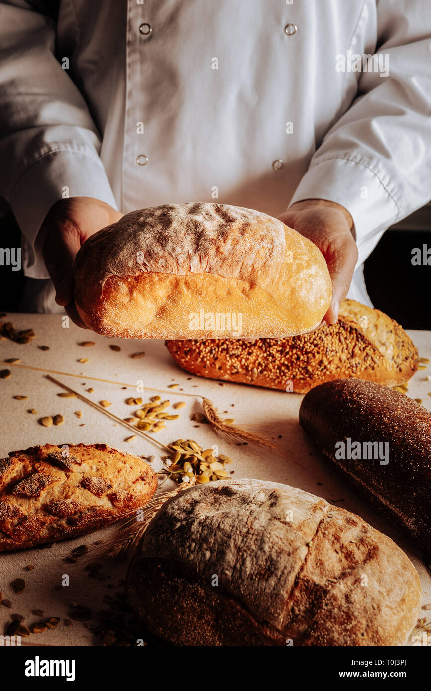 Baker in white jacket holding nice white bread in his hands Stock Photo ...
