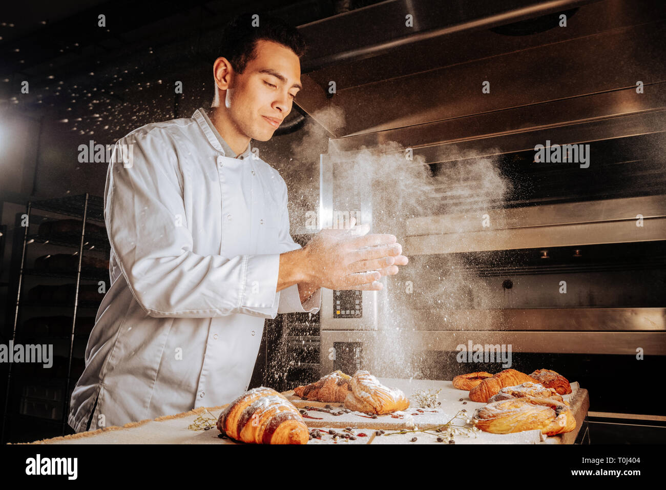 Baker clapping his hands and spilling sugar powder on pastry Stock ...
