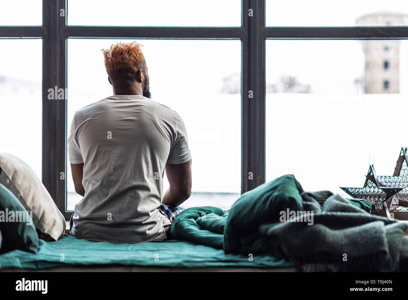 Handsome young man sitting opposite the window Stock Photo - Alamy