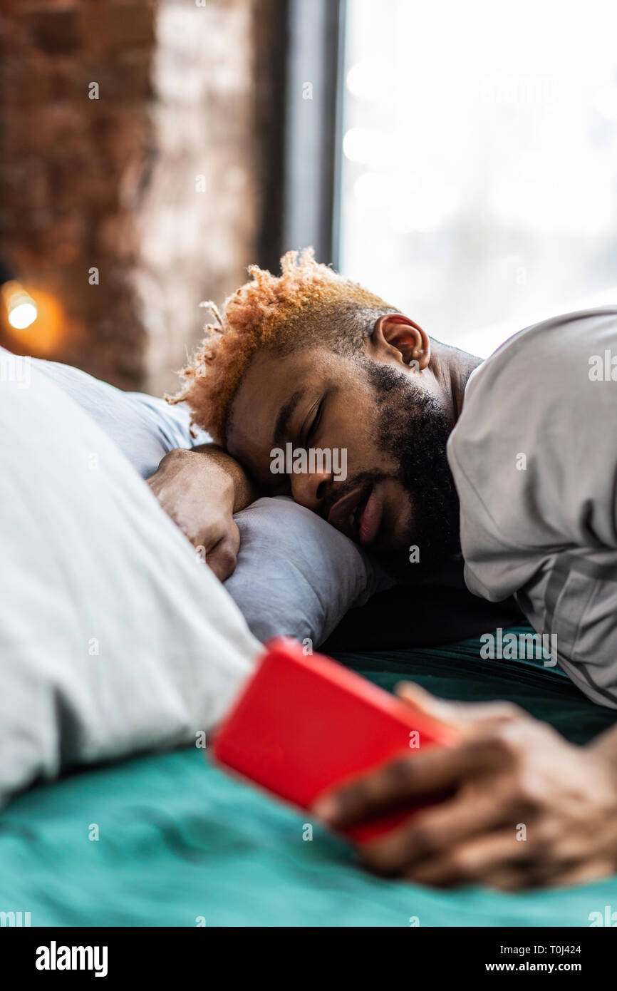 Pleasant good looking man sleeping with his phone Stock Photo - Alamy
