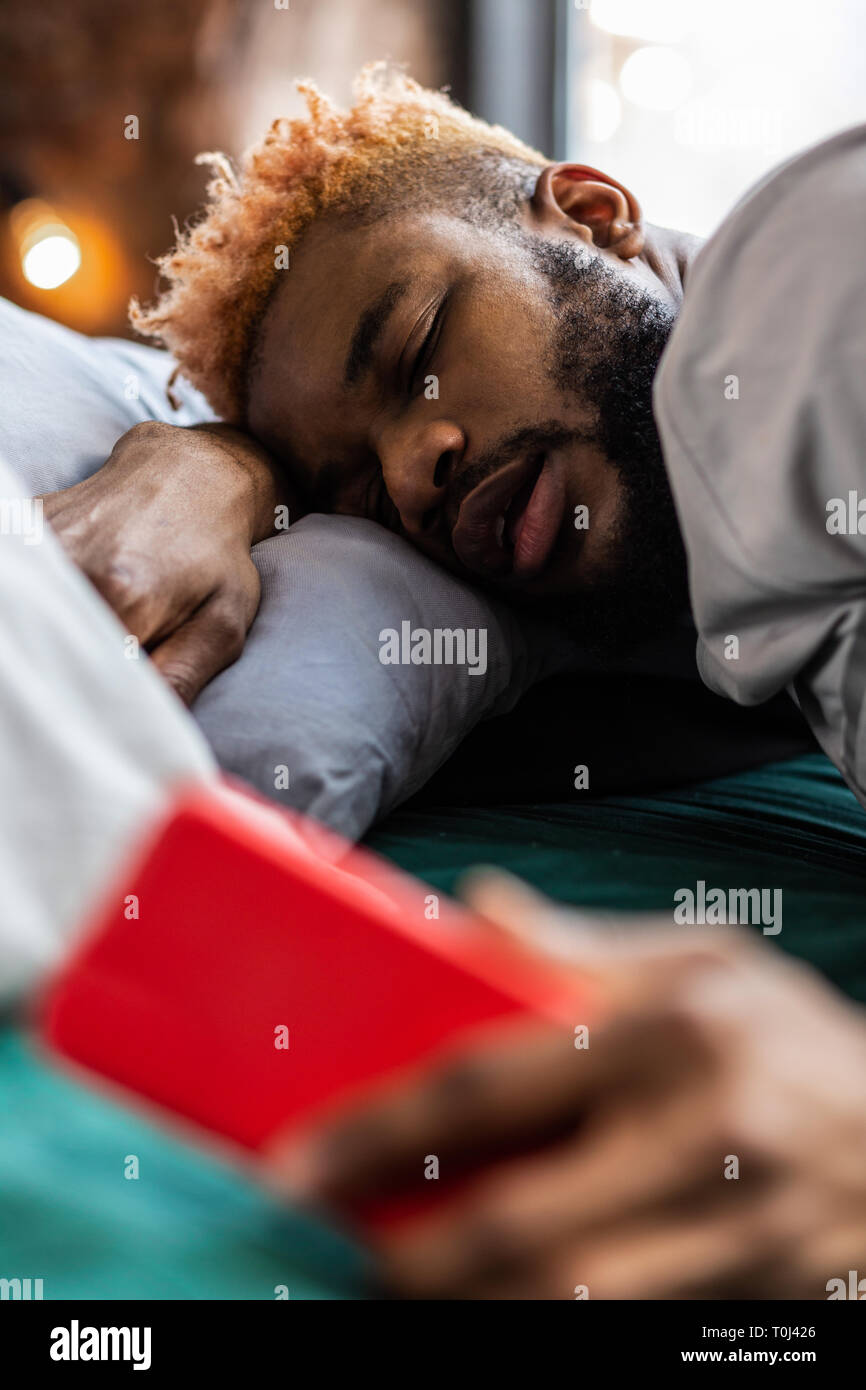 Pleasant African American man hearing the alarm clock Stock Photo - Alamy