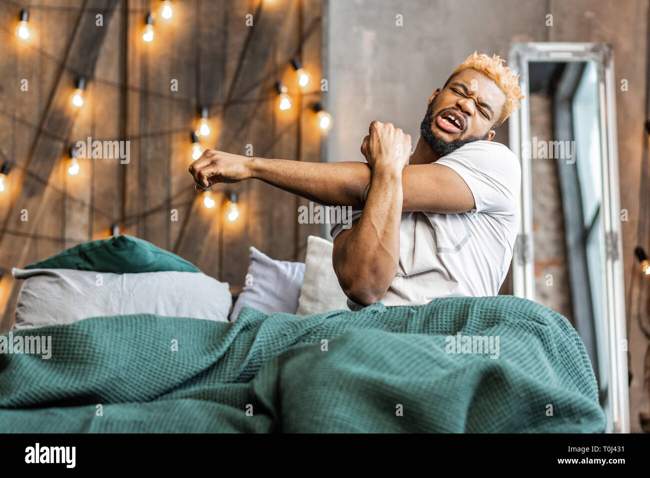 Handsome sleepy man trying to get up Stock Photo - Alamy