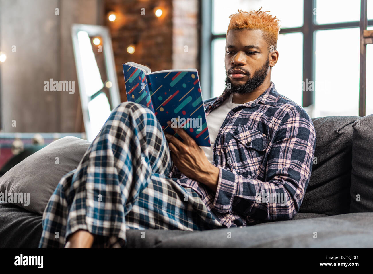 Smart nice man resting at home with a book Stock Photo - Alamy