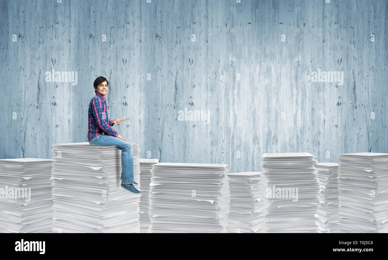 Attractive man sitting on pile of paper documents Stock Photo - Alamy