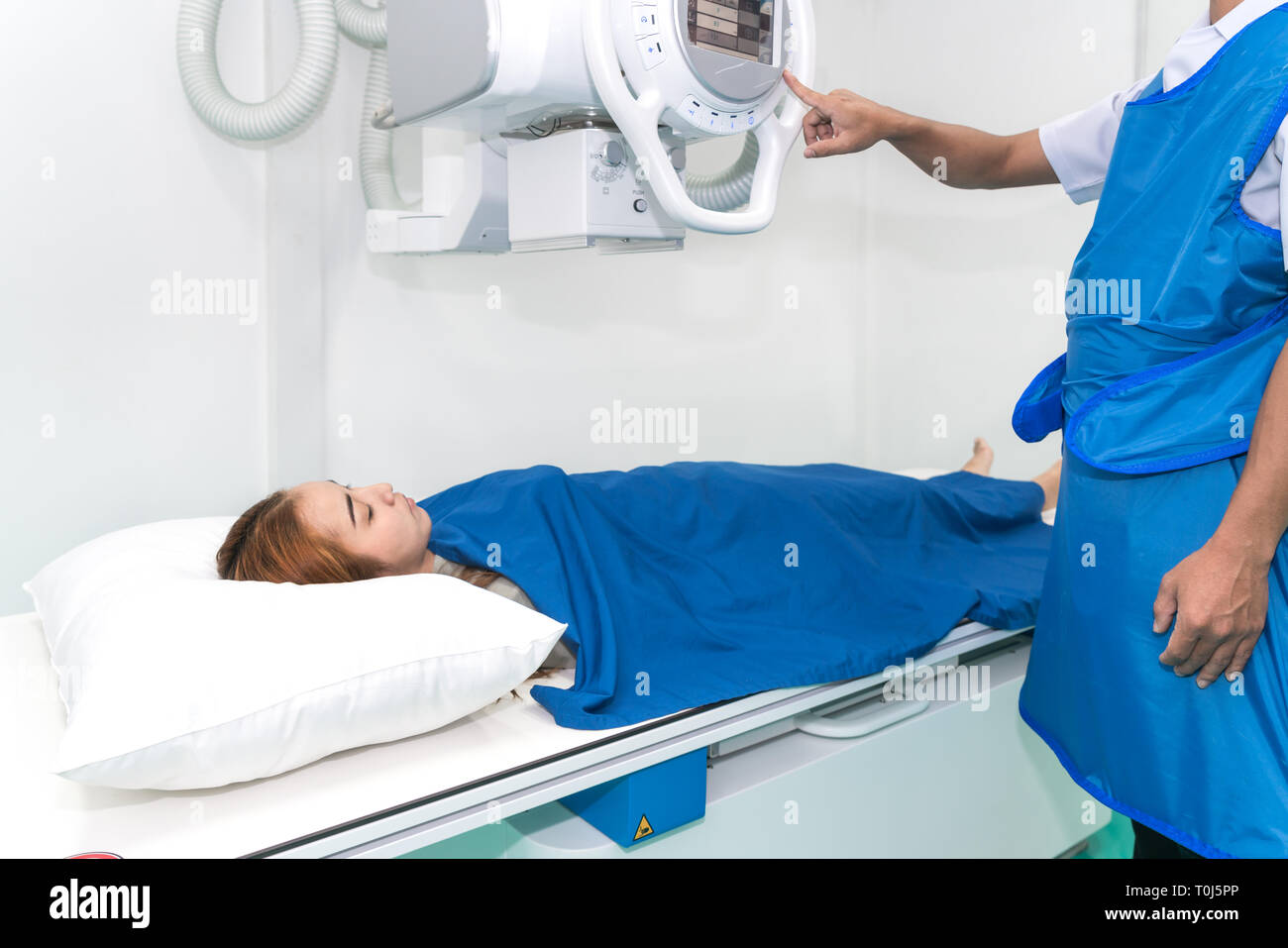 Asian young woman patient lying under X-ray device with radiologist ...
