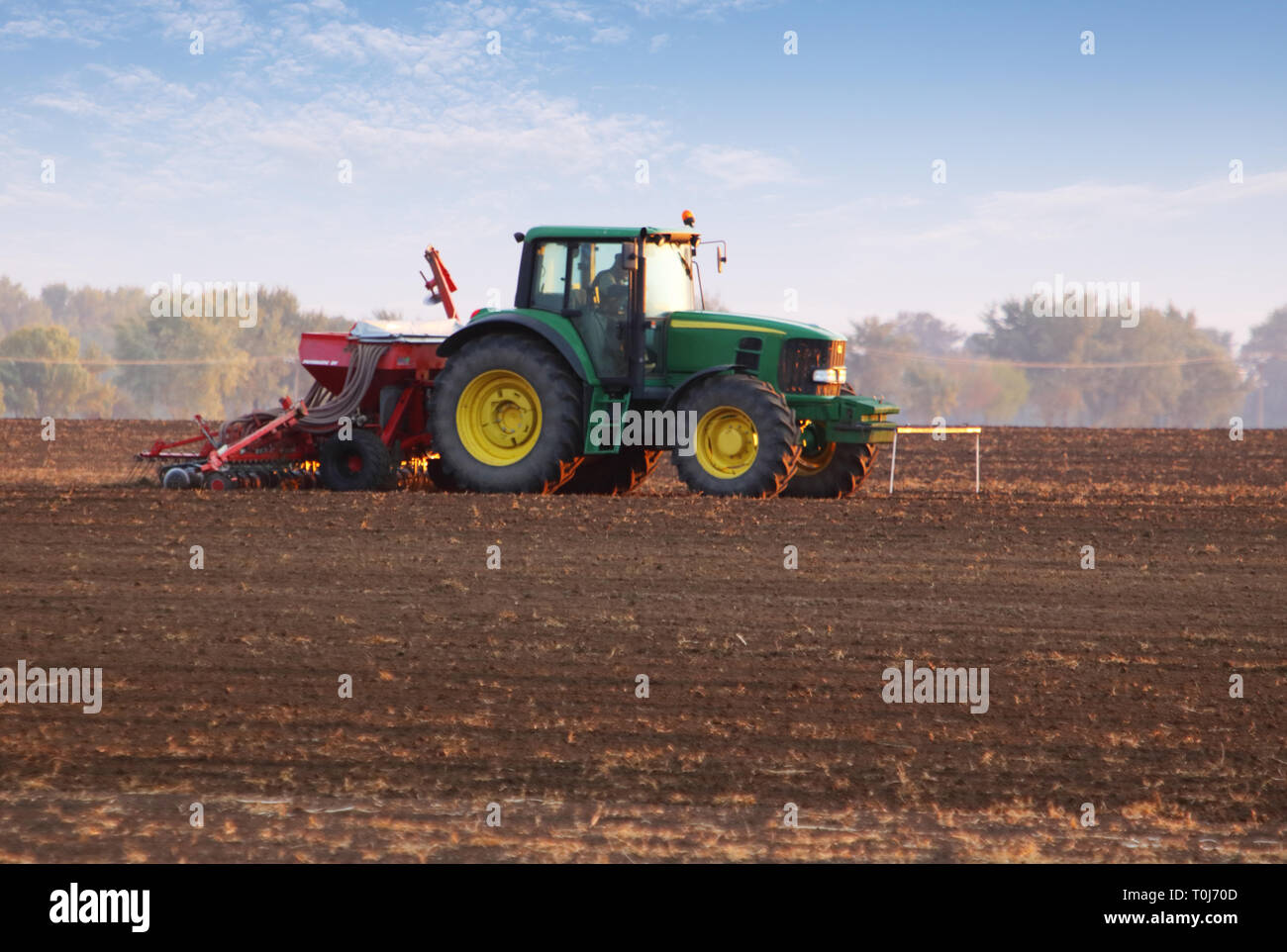 Tractor on field at sunset Stock Photo - Alamy