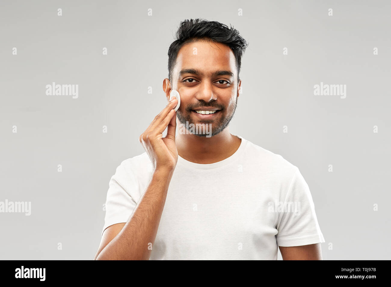 smiling indian man cleaning face with cotton pad Stock Photo - Alamy