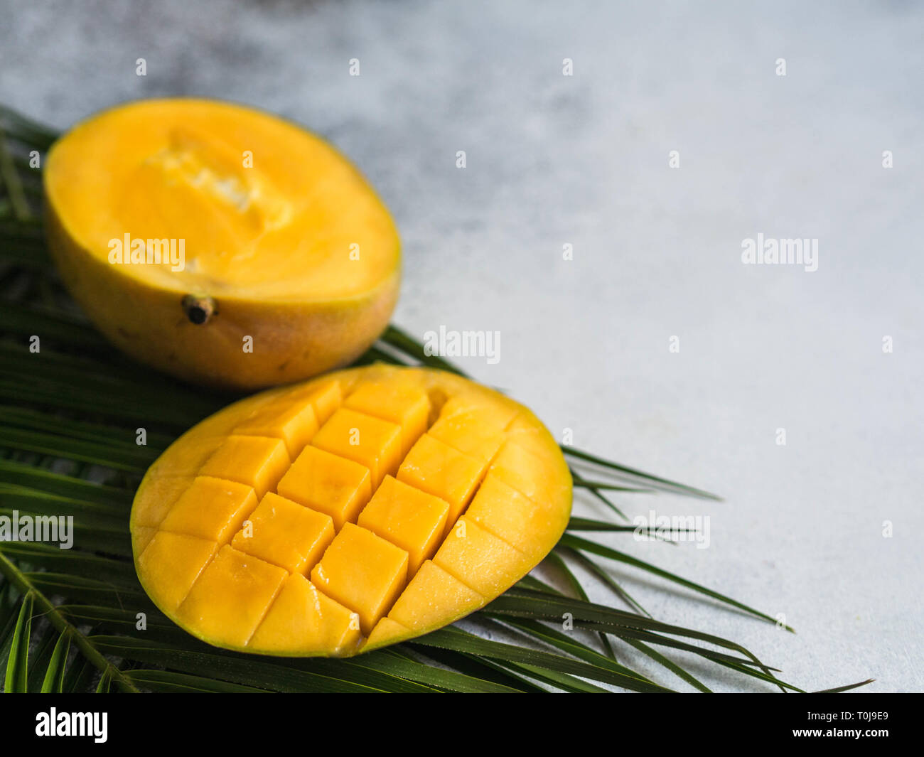 Ripe yellow mango slice on palm tree leaves on gray background Stock ...