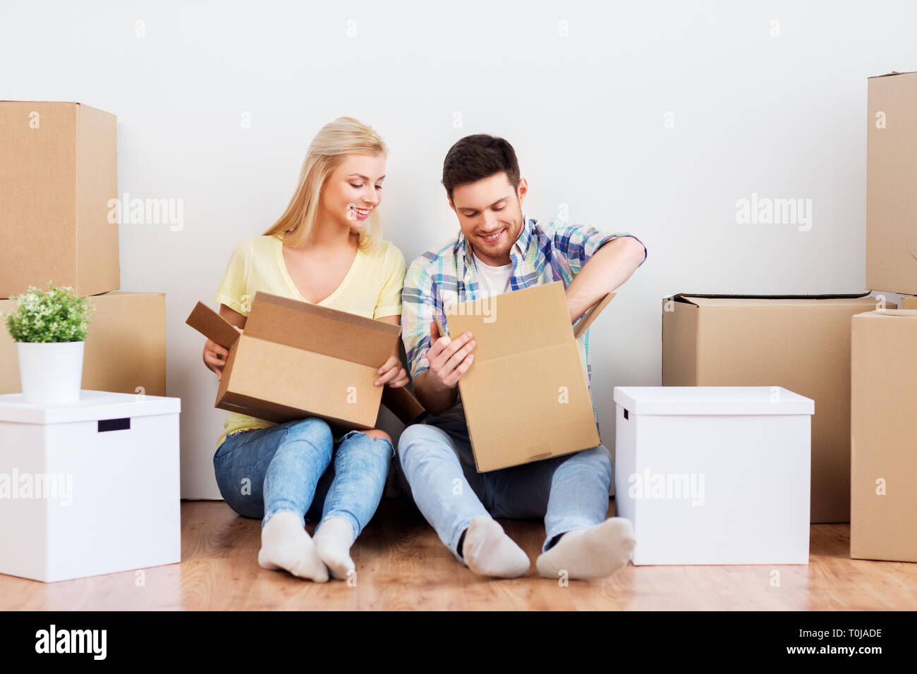 happy couple unpacking boxes at new home Stock Photo - Alamy