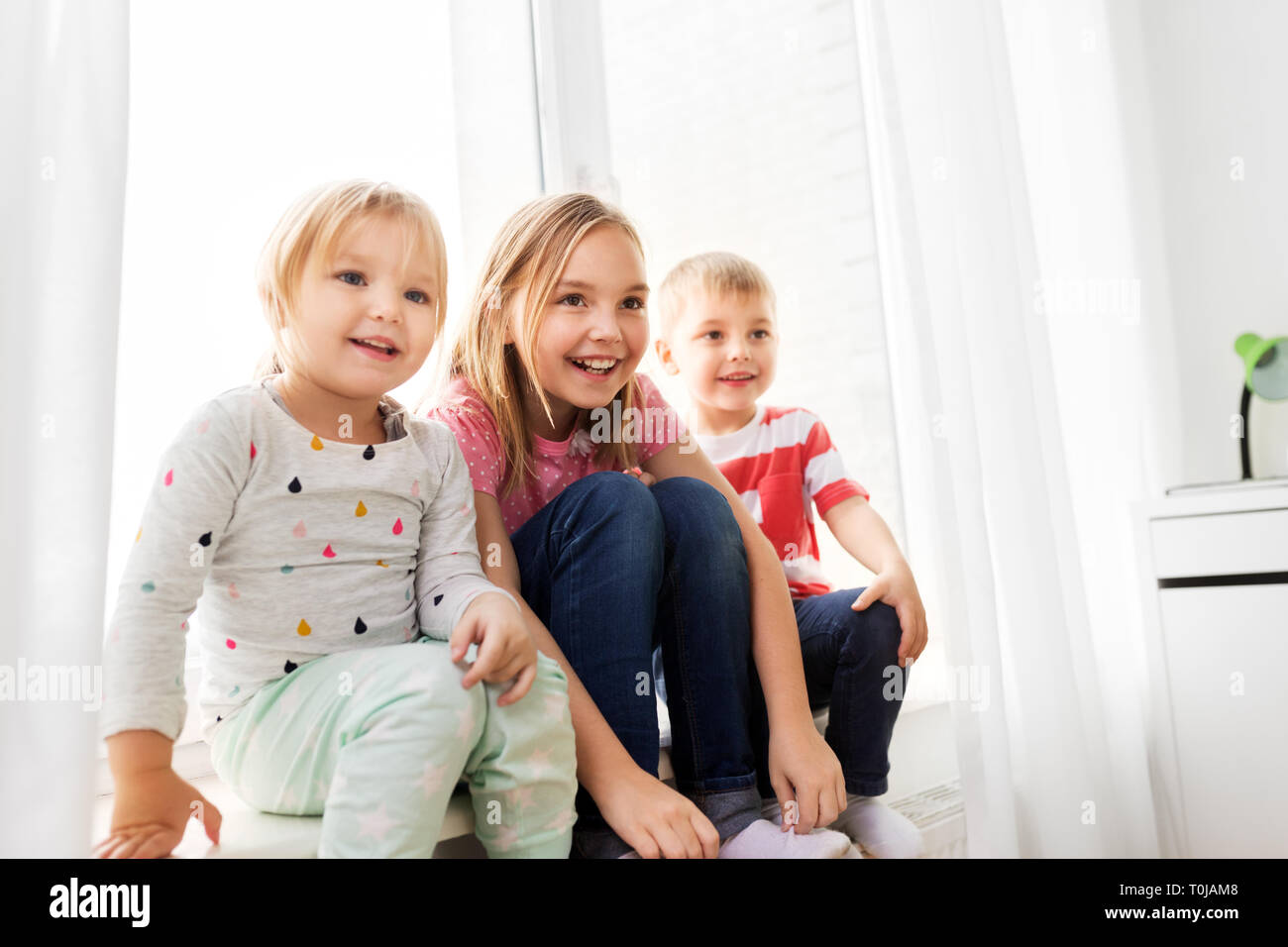 happy little kids sitting on window sill Stock Photo - Alamy