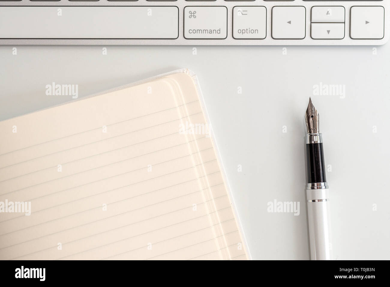 white table with notepad, keyboard and fountain pen. View from above ...
